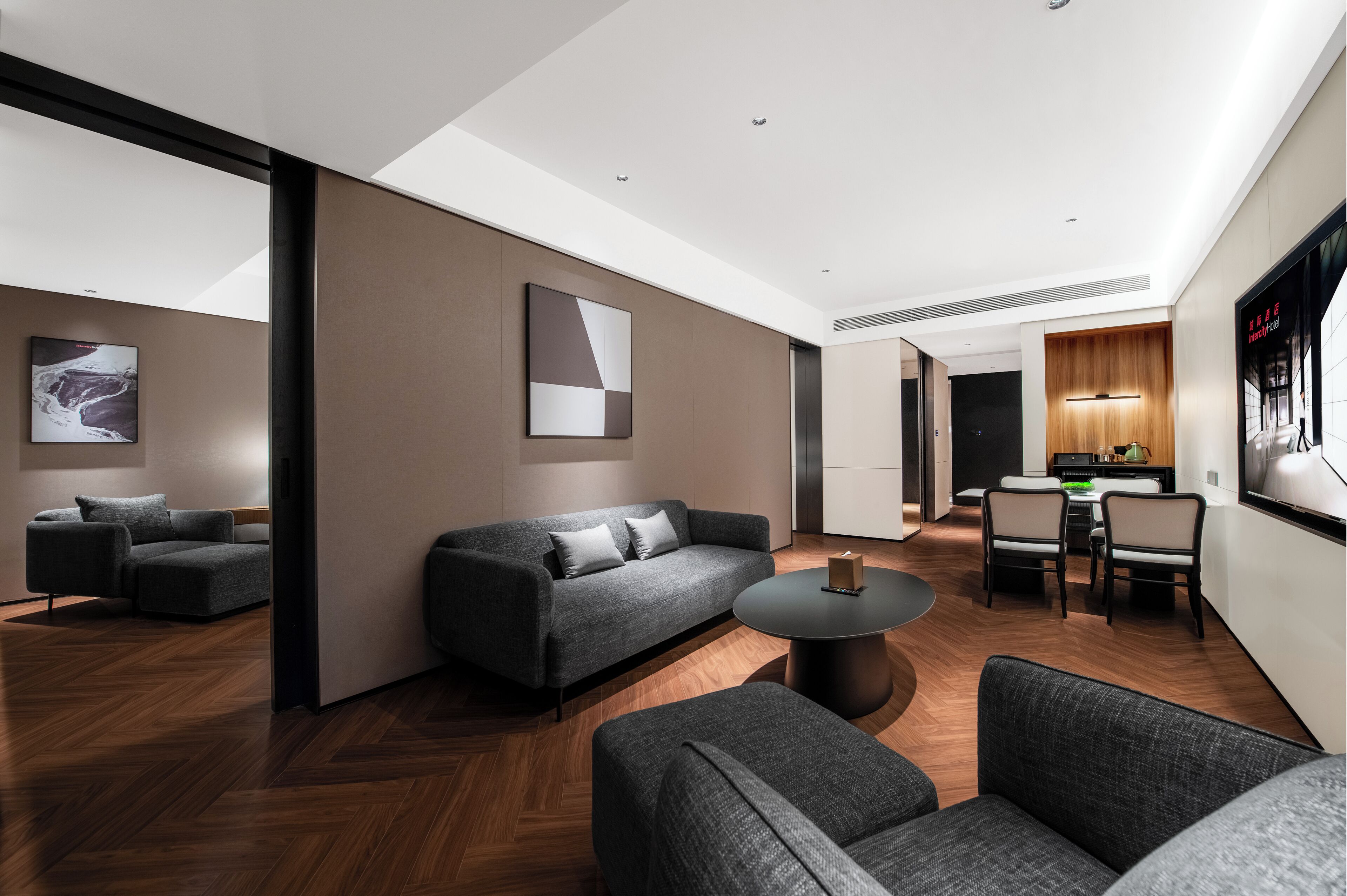 Quarto de hotel moderno com sofá, mesa de jantar e cozinha.