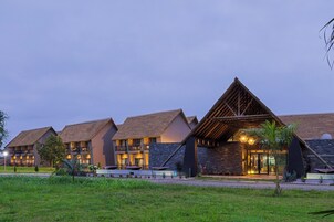 Um hotel com vários edifícios, uma construção com telhado de colmo e uma entrada bem iluminada.