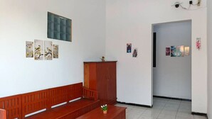 Quarto com um banco de madeira, uma mesa pequena, um armário e obras de arte na parede.