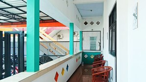 Um corredor com escadas, um corrimão e uma fileira de cadeiras vermelhas.