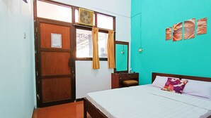Quarto com cama, guarda-roupa de madeira, janela com cortinas e uma parede com obras de arte.