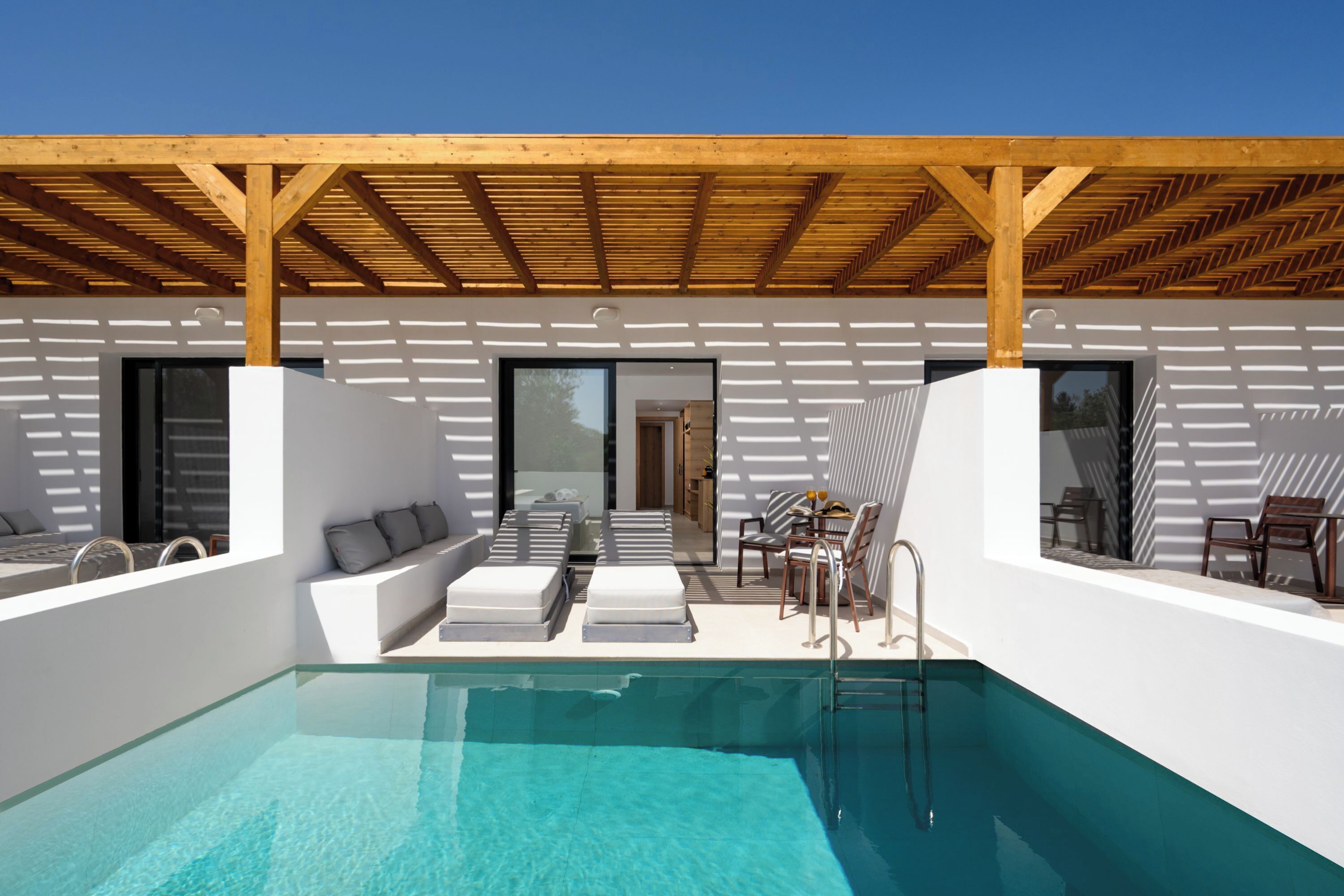 Uma área moderna de piscina ao ar livre com um pergolado de madeira, assentos de descanso e vista desimpedida para a casa.