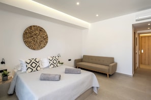 Um quarto moderno com uma cama, um sofá, uma obra de arte na parede e uma porta.