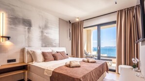 Quarto de hotel moderno com uma cama grande, vista para o mar e varanda.