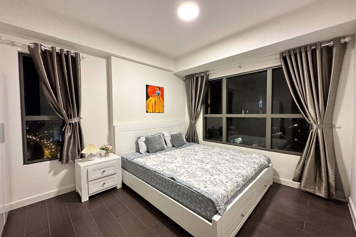 Quarto com cama, mesa de cabeceira e um quadro na parede.