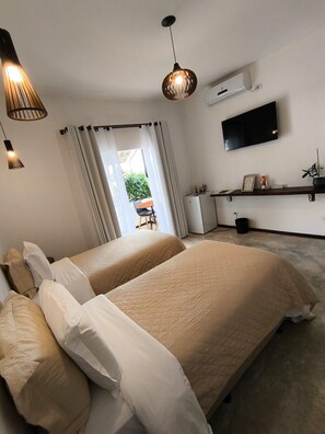 Quarto com duas camas, uma televisão, uma estante com objetos e uma janela com cortinas.