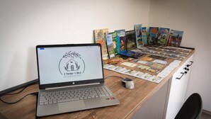 Um laptop sobre uma mesa de madeira com uma caneca de café, cercado por folhetos de viagem.