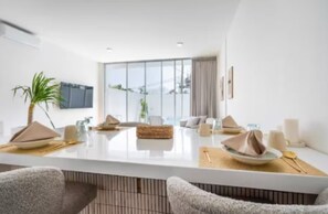 Cozinha moderna com ilha central, espaço de refeições com cadeiras e uma janela grande que oferece uma vista.