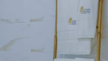 Suporte de toalhas de bambu com toalhas brancas exibindo logotipos.
