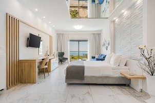 Quarto de hotel moderno com cama, escrivaninha, cadeira e varanda com vista.