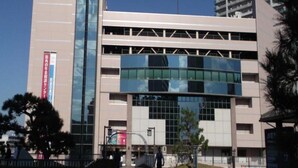 Um edifício moderno com vários andares, com grandes janelas de vidro e um telhado plano.