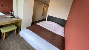 Quarto de hotel com cama, escrivaninha, cadeira e espelho.
