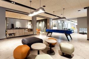 Um lobby moderno com mesa de pebolim, áreas de estar e balcão de recepção.