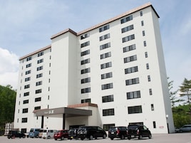 Hotel de vários andares com fachada plana, várias janelas e área de entrada coberta.