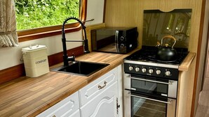 Cozinha compacta com pia, micro-ondas, chaleira e fogão.
