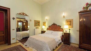 Quarto com uma cama grande, duas mesas de cabeceira com luminárias, um espelho e uma porta vermelha.