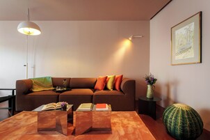 Uma sala de estar moderna com um sofá, uma mesa de centro, um abajur e um quadro na parede.