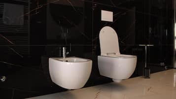 Um banheiro moderno com piso de mármore, um bidê branco e um vaso sanitário.