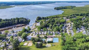 Vista aérea de um camping com veículos recreativos, piscina e quadra de tênis.