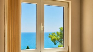 Uma janela com vista para o mar e uma árvore.