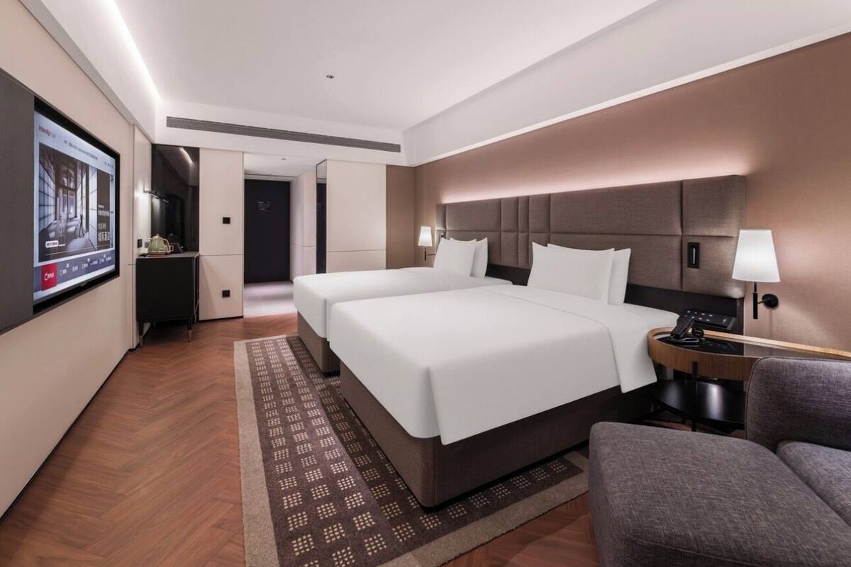 Quarto de hotel com uma cama grande, duas mesas de cabeceira, uma televisão e um espaço de estar.