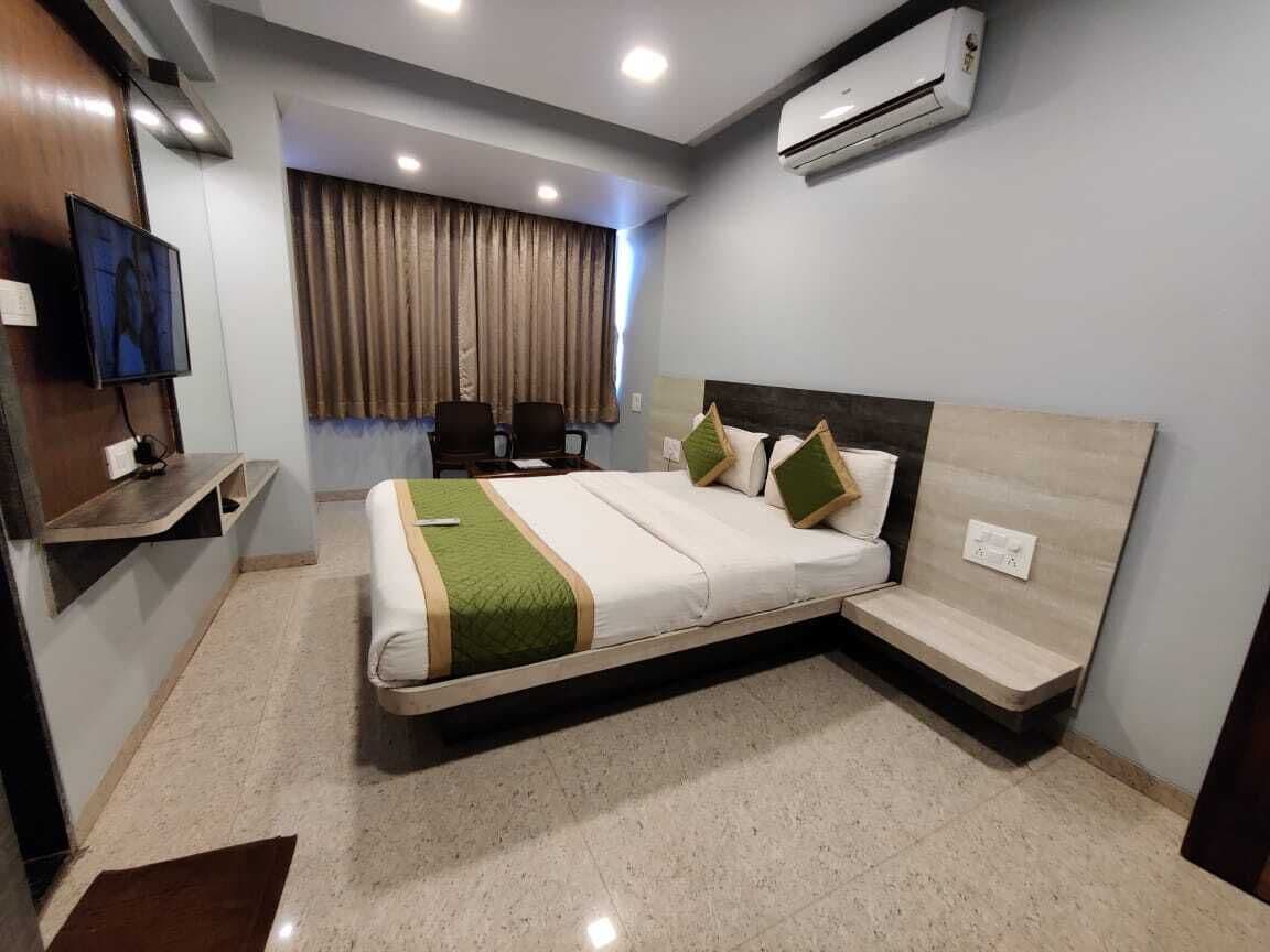 Quarto de hotel com cama, escrivaninha, cadeira, ar condicionado e televisão.