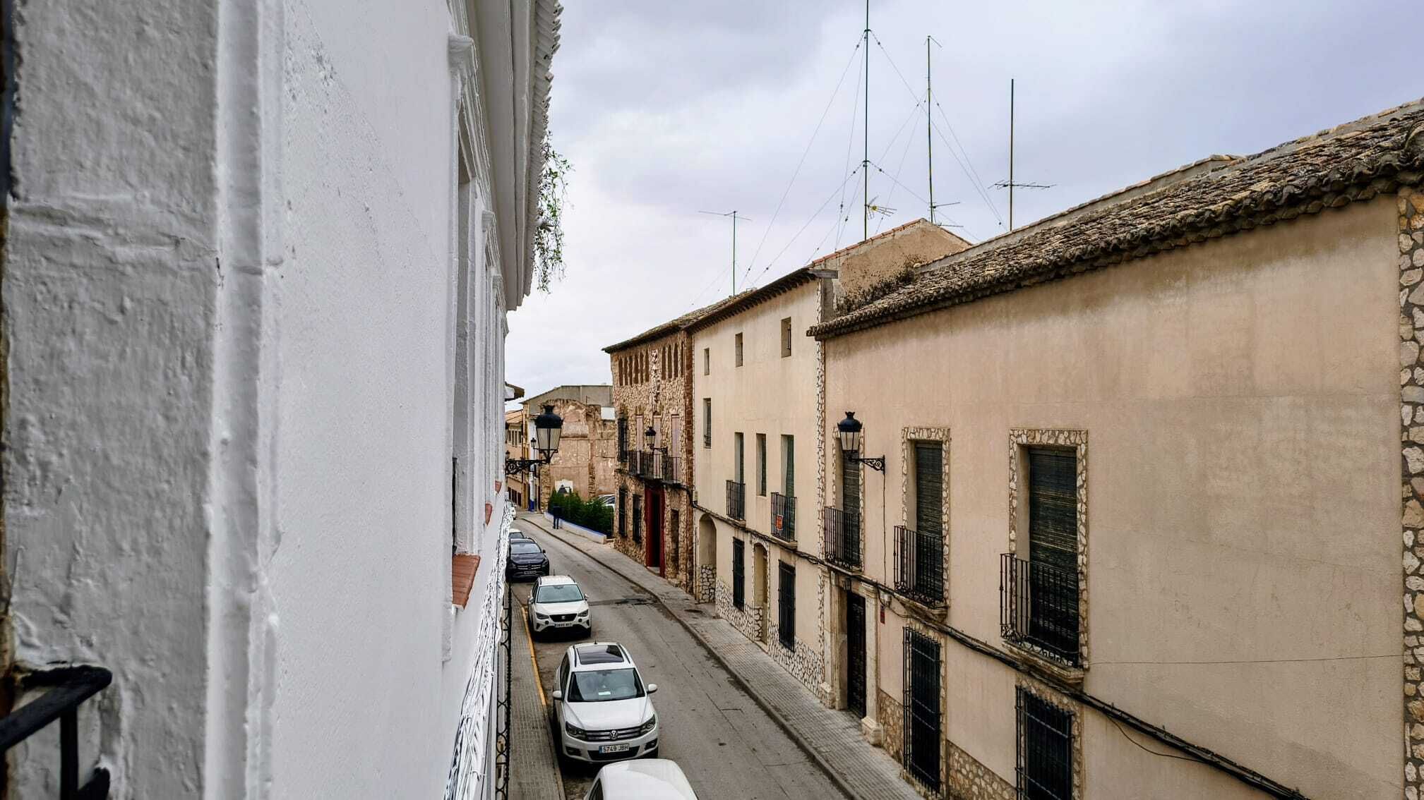 Ruas estreitas com carros estacionados, edifícios tradicionais e antenas nos telhados.