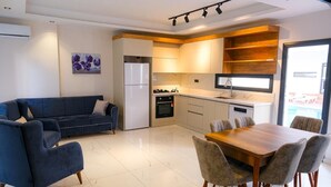 Uma cozinha moderna com forno embutido, geladeira e um espaço de jantar com mesa e cadeiras de madeira.
