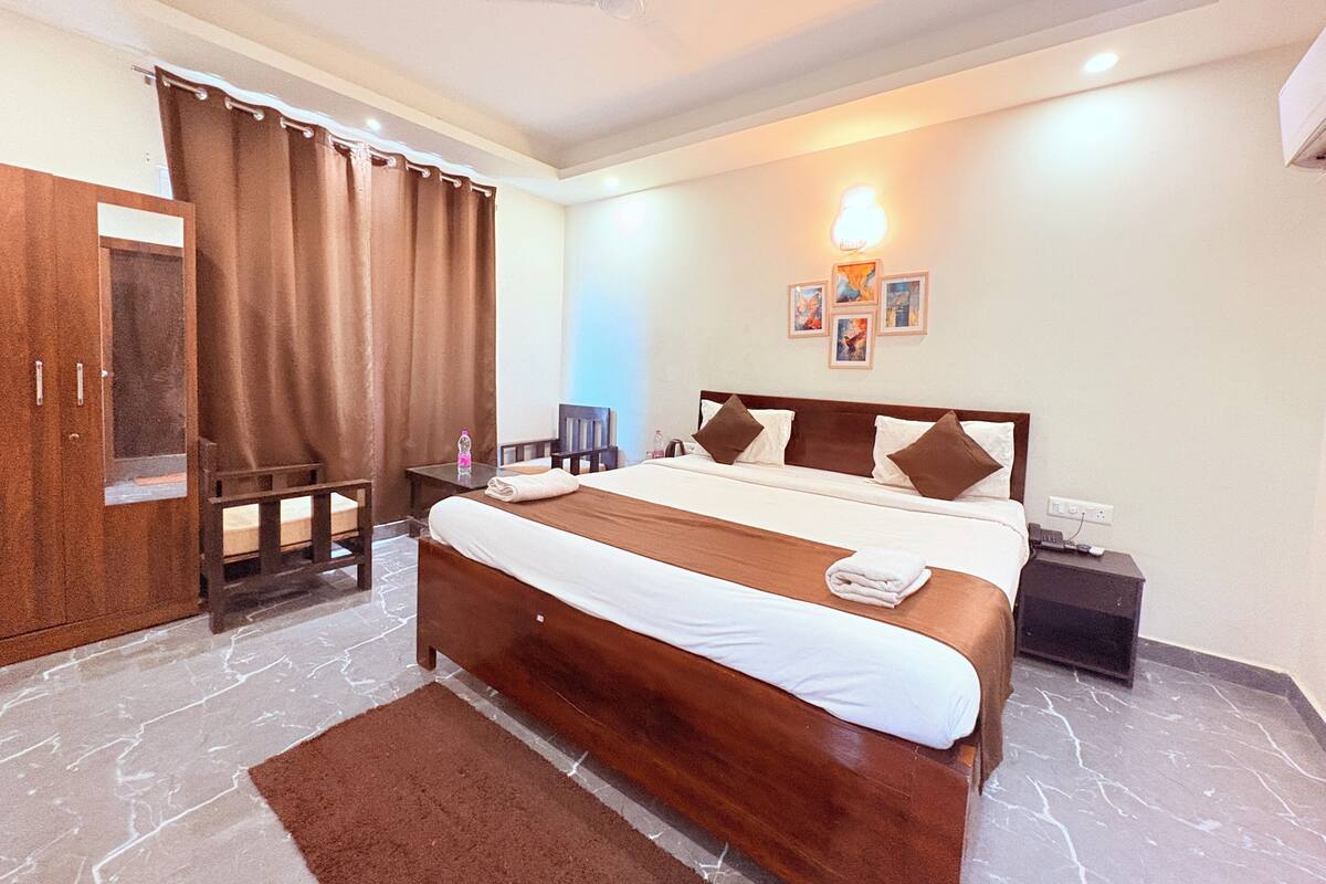 Quarto de hotel com cama, escrivaninha, cadeira, guarda-roupa e ventilador de teto.