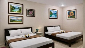 Quarto de hotel com duas camas, uma mesinha de cabeceira e quadros nas paredes.