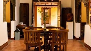 Uma área de refeições com mesa e cadeiras de madeira, luminária pendente e piso de azulejos.