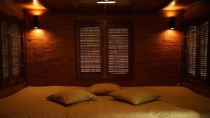 Quarto com cama de madeira, duas luzes fixadas na parede e janela com persianas.