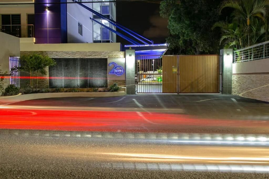 Entrada de hotel com uma entrada por portão, uma placa com o número '2' e fachada de um edifício moderno.