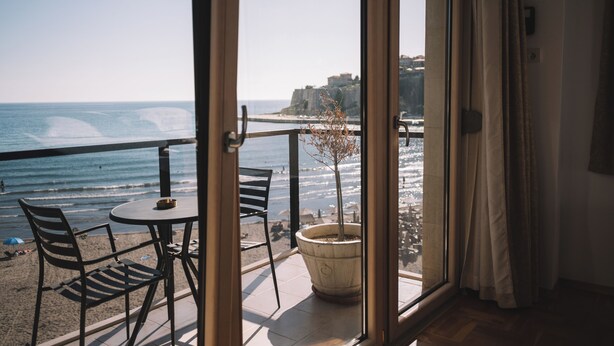 Varanda com vista para o mar, um vaso de planta e uma mesa com cadeiras.