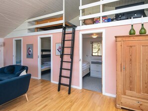 Um quarto no estilo loft com escada de madeira, beliches, escrivaninha e guarda-roupa.