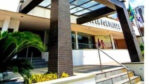 Um edifício moderno com fachada de vidro, entrada visível e escadaria que leva à entrada.