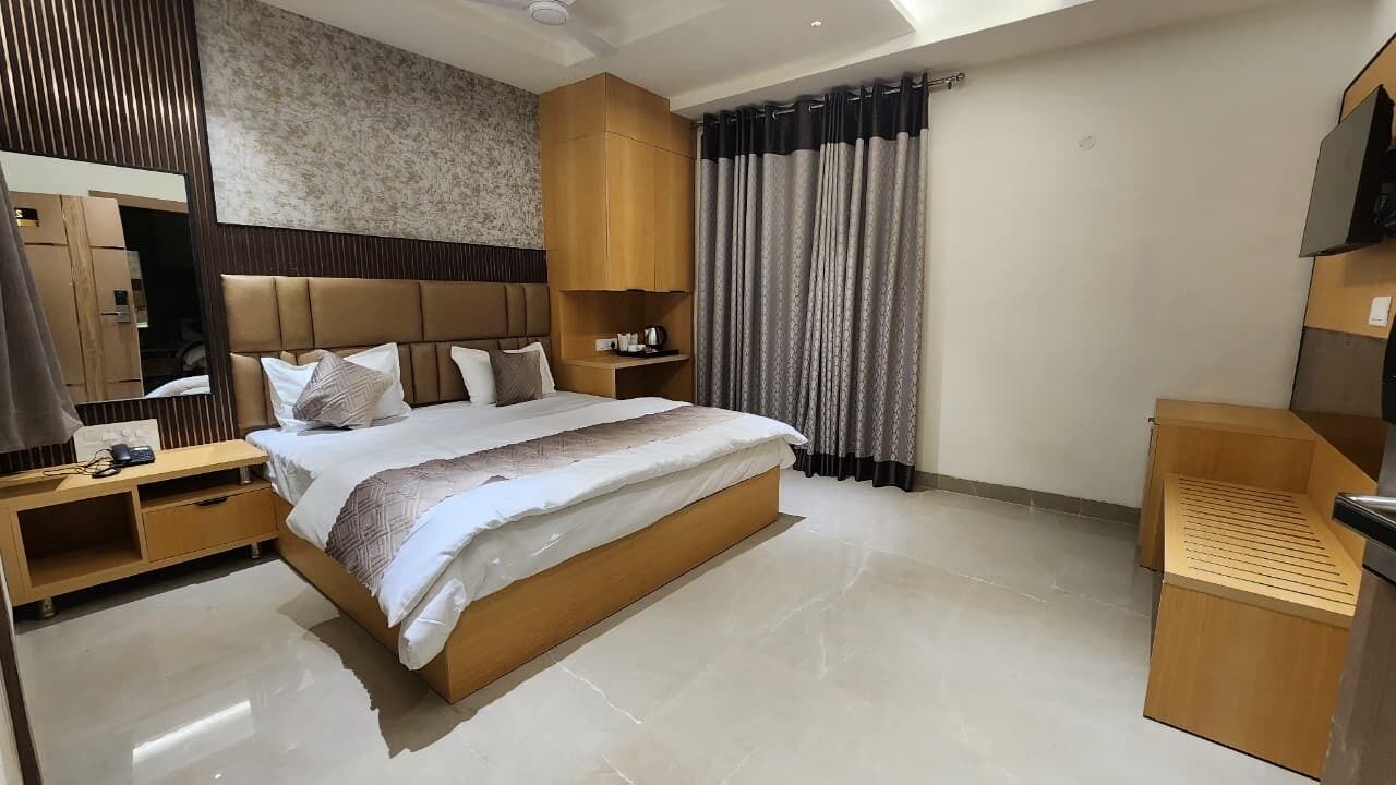 Quarto de hotel moderno com uma cama grande, cabeceira de madeira, mesas de cabeceira, um espelho e um guarda-roupa.
