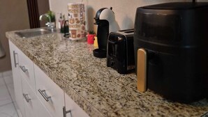 Cozinha com micro-ondas, torradeira e cafeteira no balcão.
