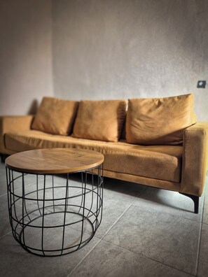 Uma sala de estar moderna com um sofá e uma mesa de centro redonda com estrutura de arame.