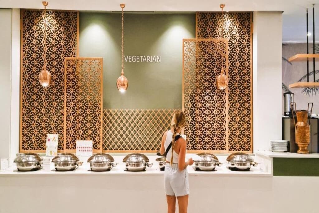 Uma área de buffet com uma placa que diz 'VEGETARIAN' e painéis decorativos.
