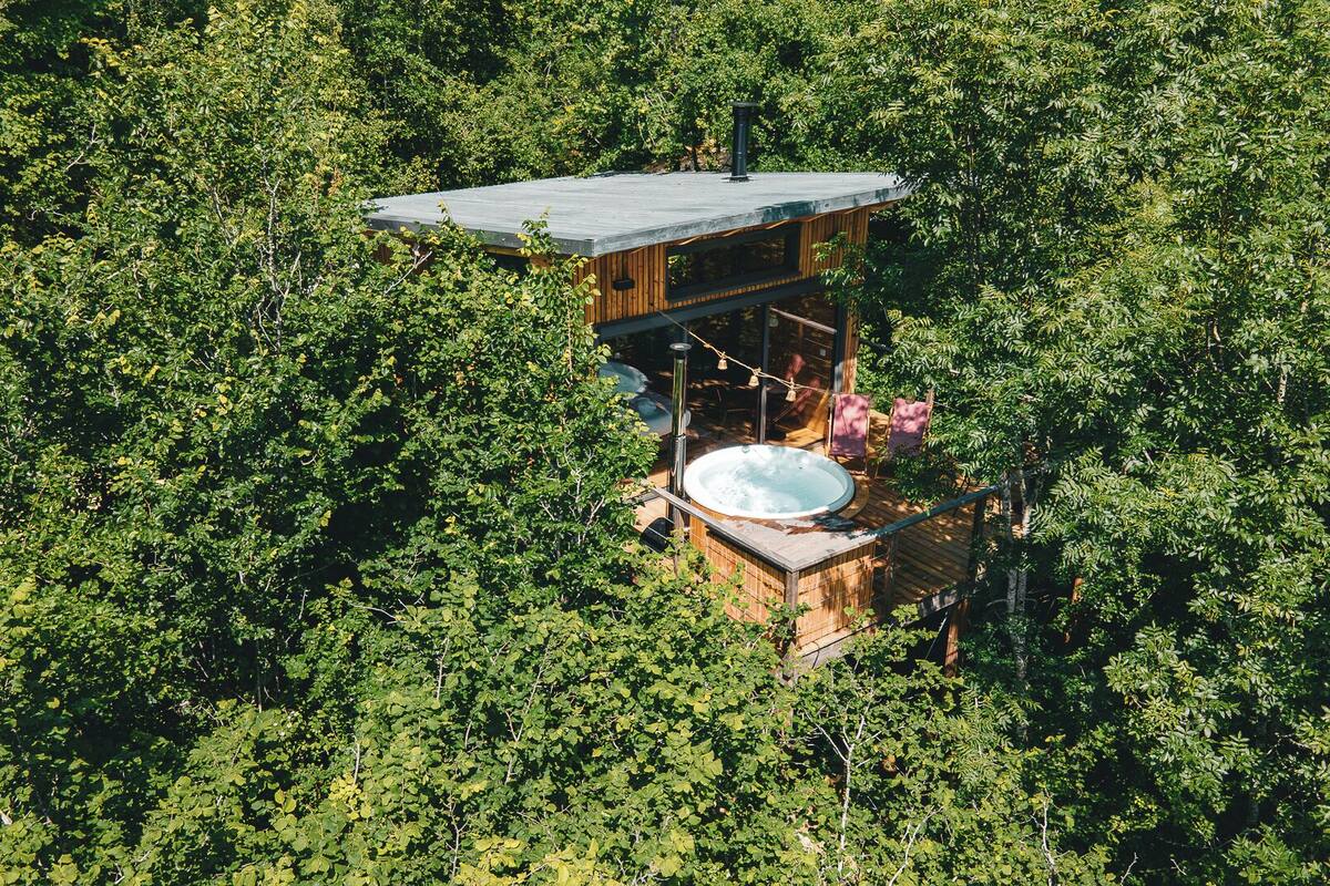 Uma cabana de madeira com hidromassagem, rodeada por uma floresta densa.