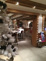 Um interior acolhedor com árvore de Natal, vigas de madeira, área de bar e espaço para sentar.