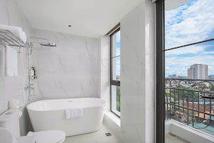 Uma casa de banho moderna com uma banheira independente, sanita e chuveiro.