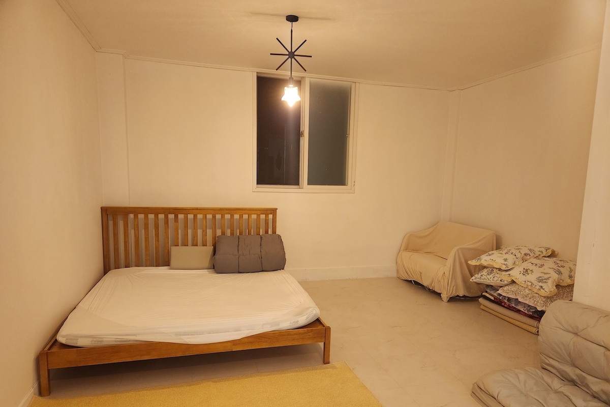 Um quarto com uma cama de madeira, uma janela, uma cadeira e um sofá.