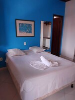 Um quarto com uma cama, um quadro na parede e um espelho.
