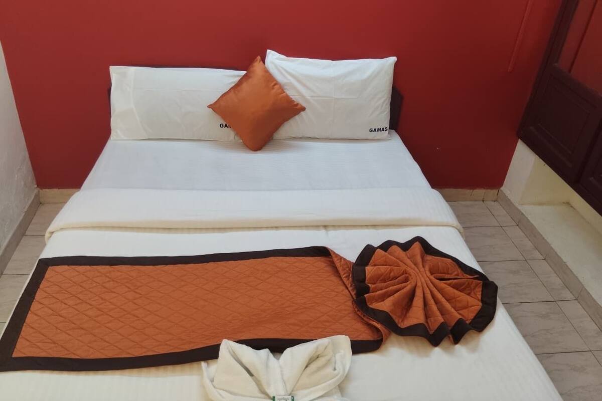 Uma cama com roupa de cama branca, um travesseiro marrom e um cobertor marrom.