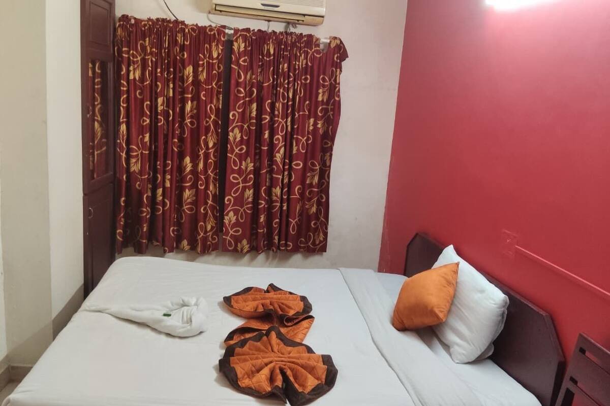 Quarto com uma cama, janela com cortinas estampadas e ar-condicionado fixado na parede.