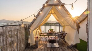 Terraço no terraço com tenda, mesas e cadeiras ao ar livre, churrasqueira e luzes de Natal.