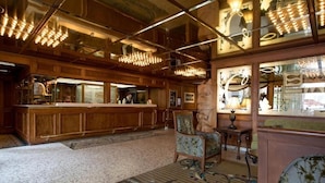 Uma área de bar com lambris de madeira, um balcão e um tapete estampado.