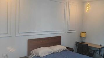 Quarto com cama, mesa de cabeceira, cadeira, escrivaninha, luminária e duas luminárias espiral.